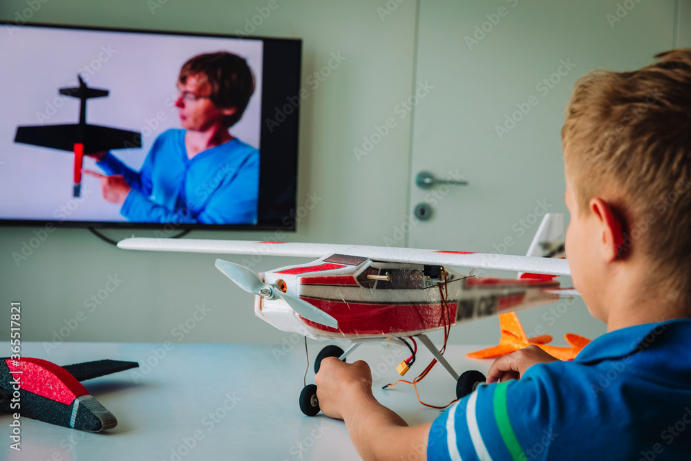 boy making model of plane with online video lesson, kids engineering ...
