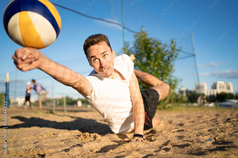 Playing volleyball on the beach, the guy hits the ball in a jump ...