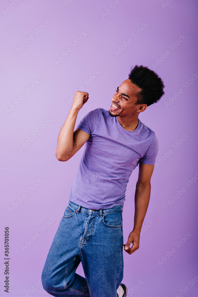 Joyful handsome male model in blue jeans expressing positive emotions ...