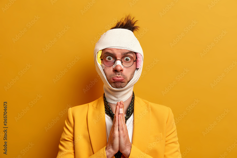 Sad displeased man keeps palms pressed togehter and asks for help, has ...