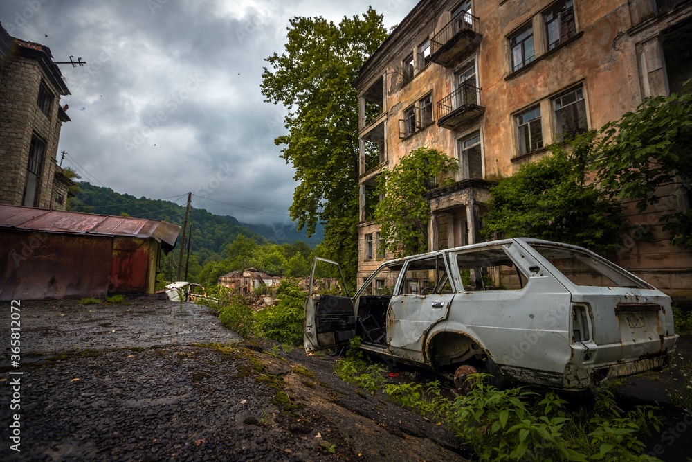 Corrupted frame of old car near abandoned brick building in former ...