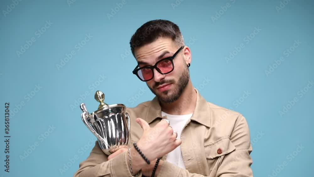 excited young guy hugging and protecting silver trophy, pointing ...