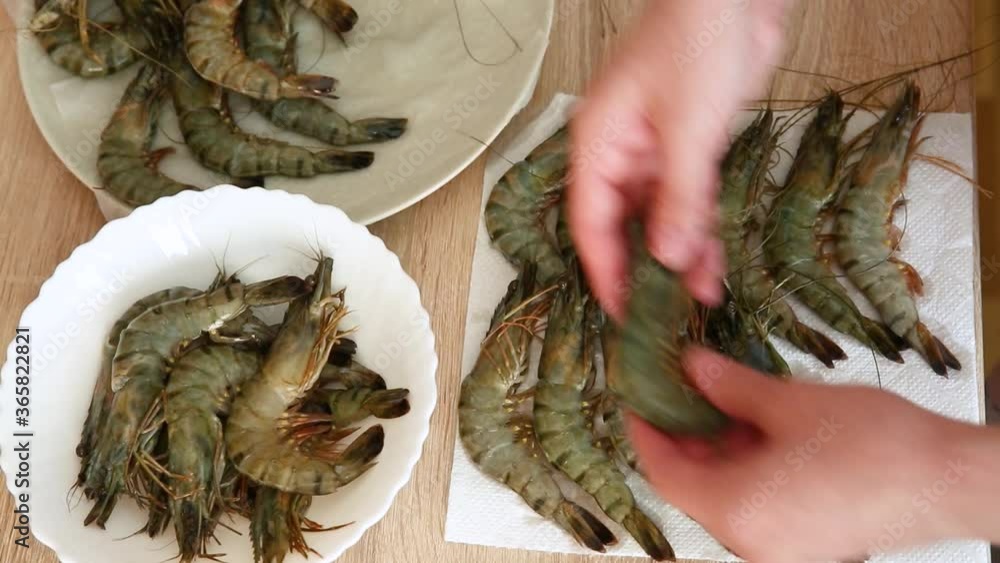 girl prepares shrimp for cooking. soaks and cuts off the antennae in ...