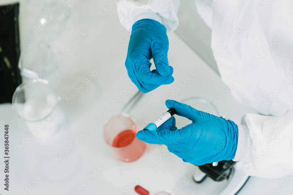 Lab Technician in Personal protective equipment PPE suit holding blood ...
