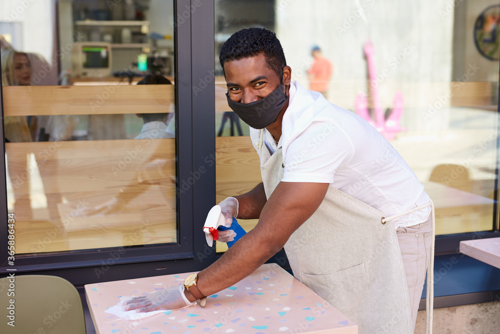 black man waiter wiping table in street cafe, pleasant staff prepare ...