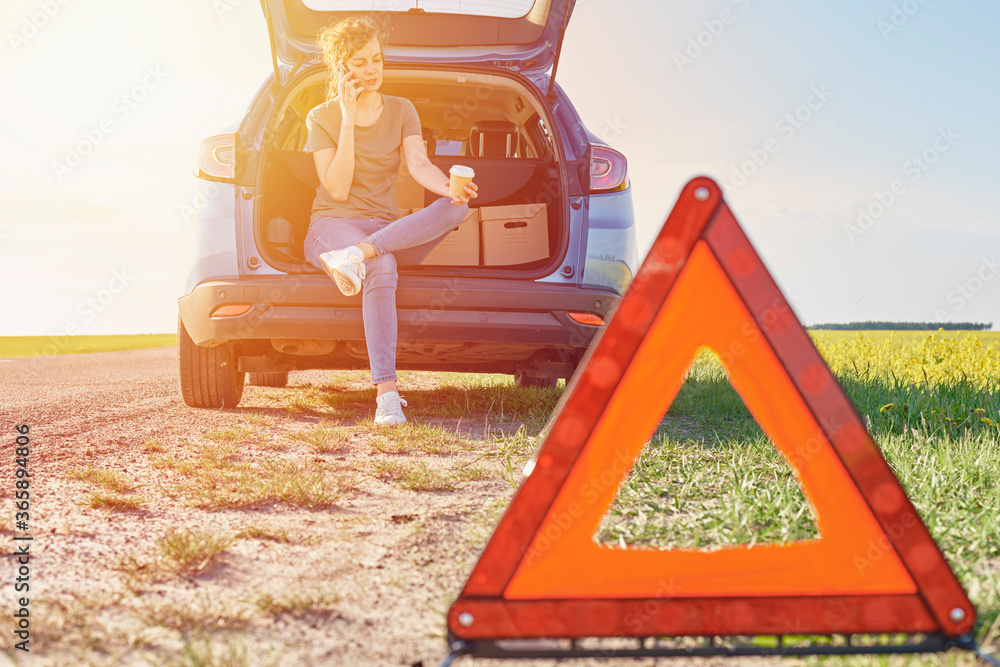 Girl calling for help near car with emergency stop sign. Woman have ...