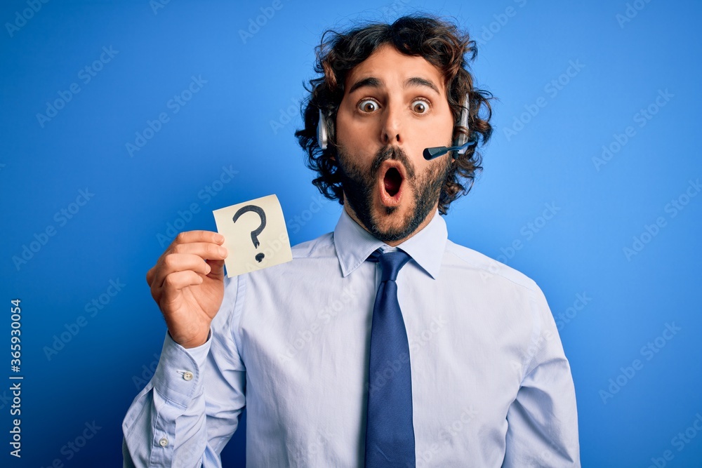 Young call center agent man with beard working using headset holding ...