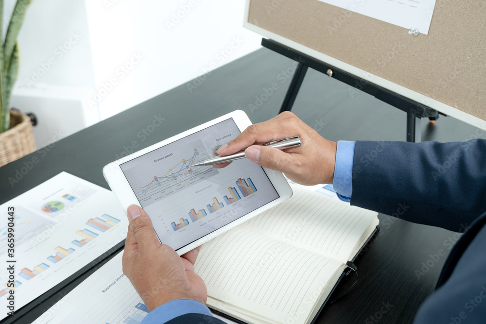 The hands of an adult businessman holding a pen are analyzing and ...