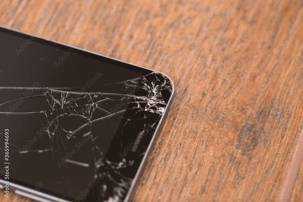 A broken phone is on the floor. Smartphone cracked screen closeup ...