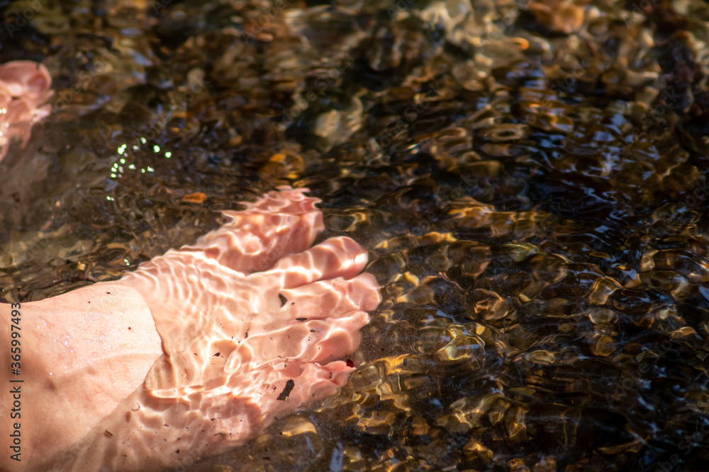 Young boy playing barefoot with clear water at a little creek using his ...