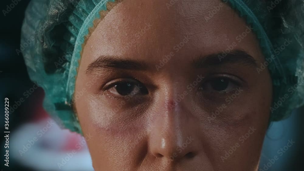 Woman doctor during a coronavirus pandemic covid-19 looks at camera, on ...