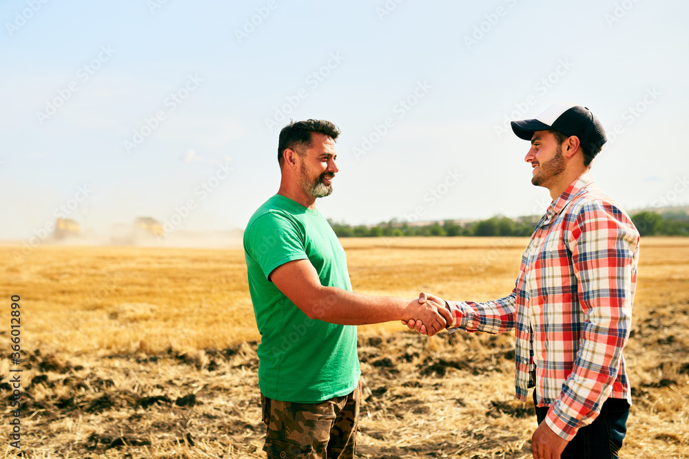 Farmer and agronomist shaking hands in wheat field after agreement ...