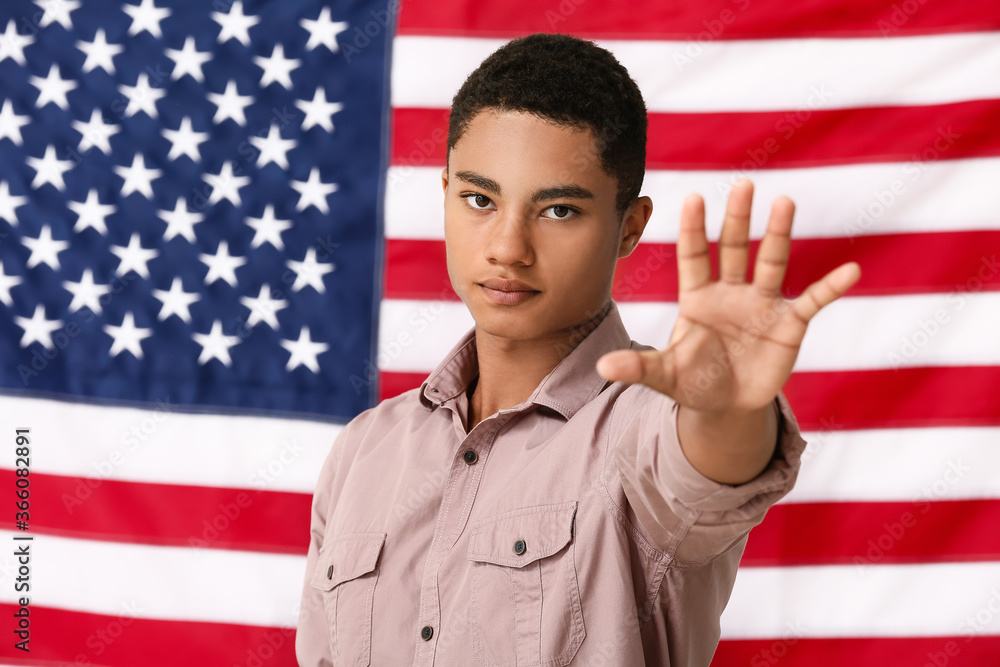 Sad African-American teenage boy near national flag of USA. Stop racism ...