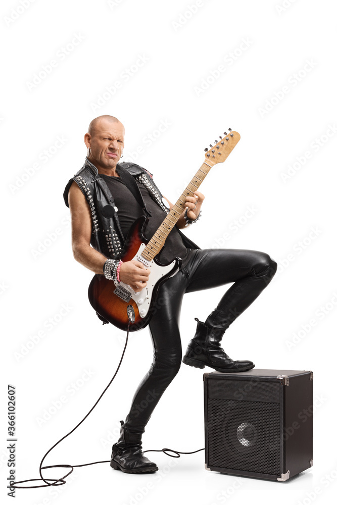 Full length shot of a rock star playing a guitar with his leg on an ...