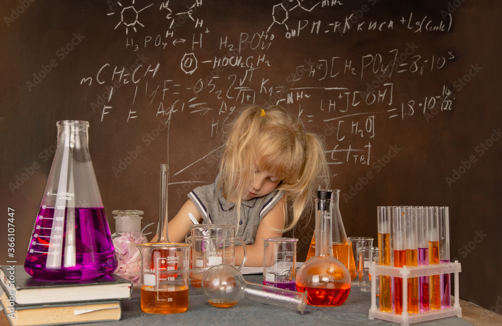 Curious little girl with test tubes and colorful substances makes tests ...