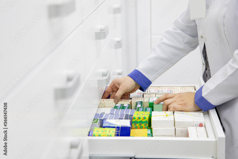 Pharmacist holding medicine box and capsule pack in pharmacy drugstore ...