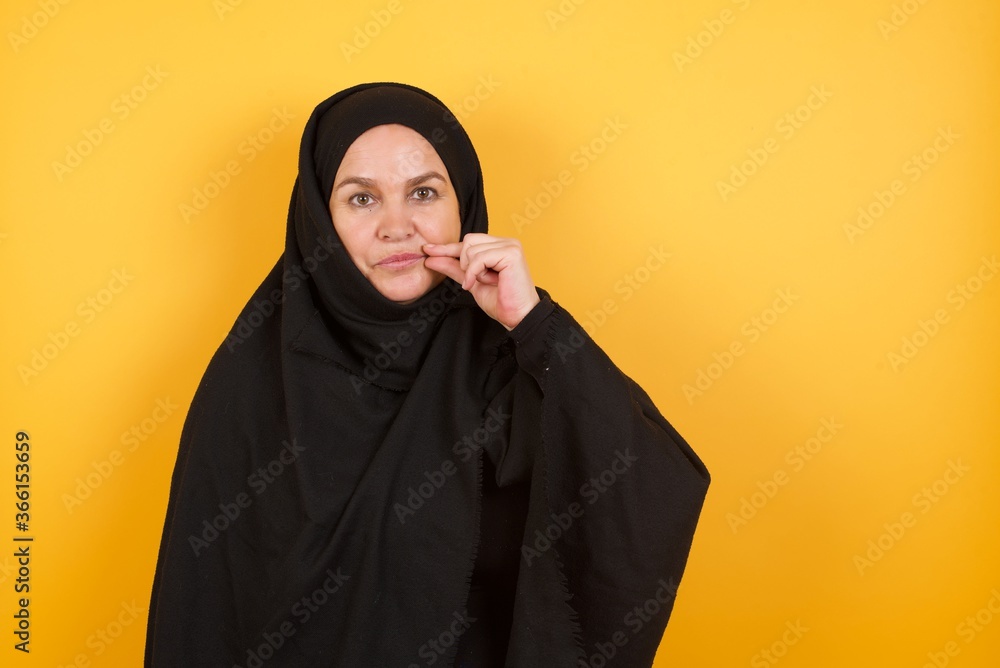 Beautiful middle aged muslim woman wearing black hijab over yellow ...