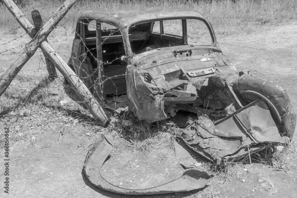Old collapsed retro car thrown on a rusty field after the war. broken ...