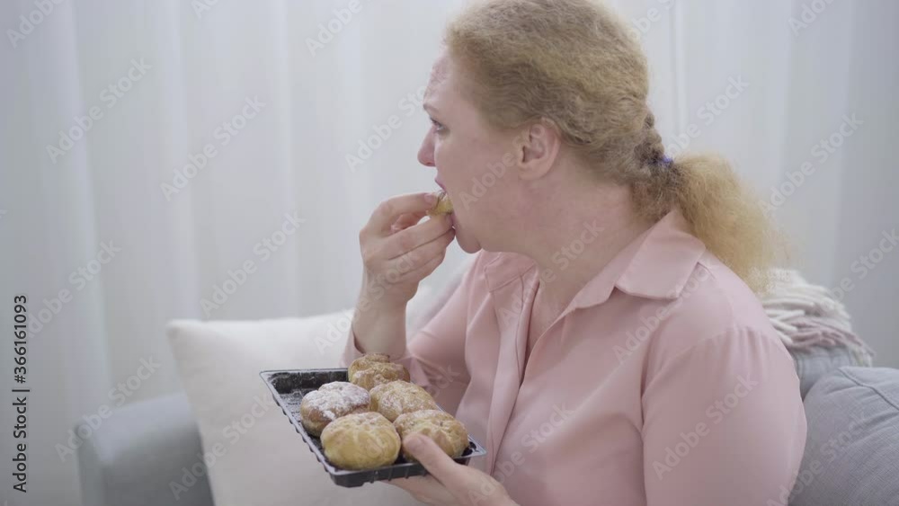 Depressed chubby woman chewing sweet buns and crying. Side view of ...