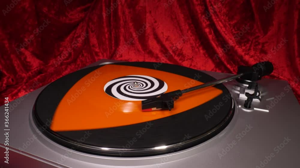 Stylus arm and needle lowered on shaped orange vinyl record on DJ ...
