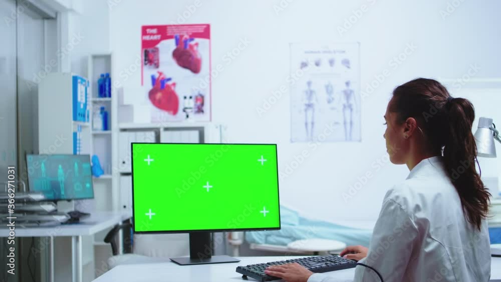 Medic writing diagnose on computer with green screen monitor while ...