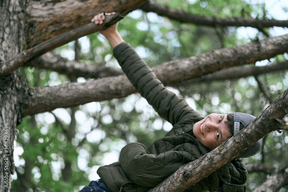 teenage boy poses on a tree, lying on a big branch and dreaming Stock ...