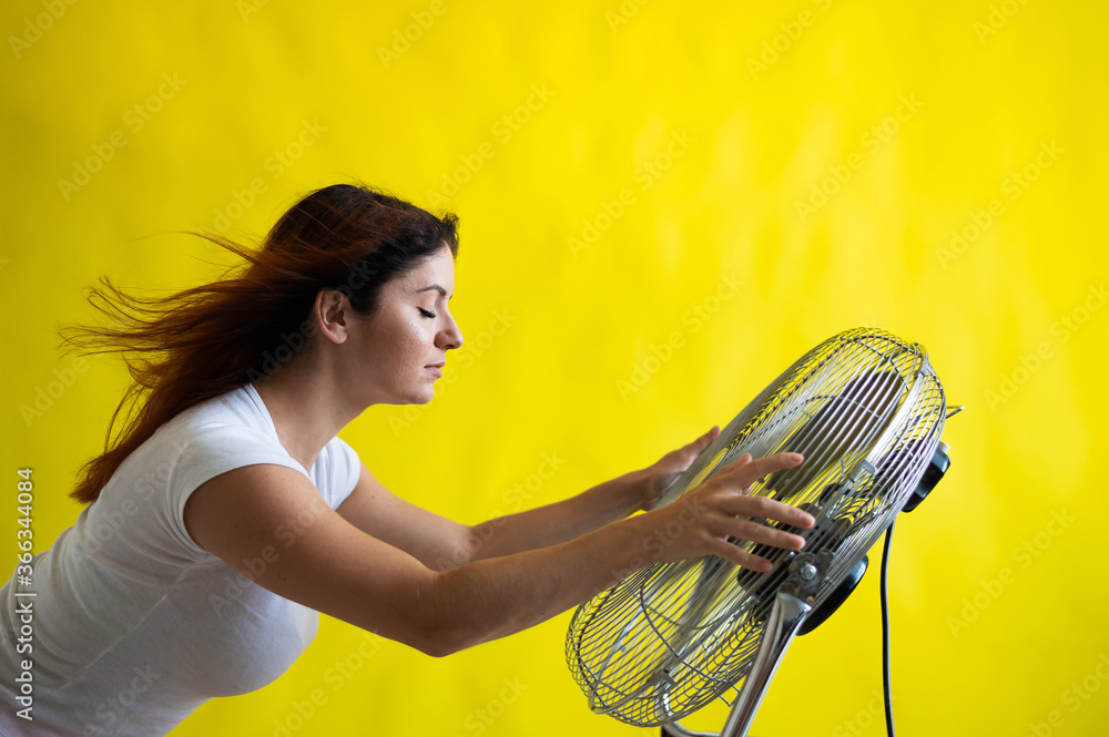 A beautiful red-haired woman is cooled off standing over a large ...
