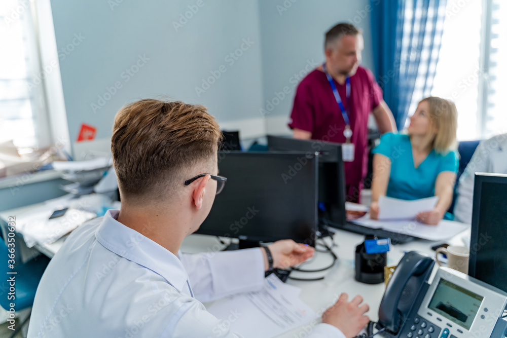 Three doctors are speaking with each other near computers. medical ...