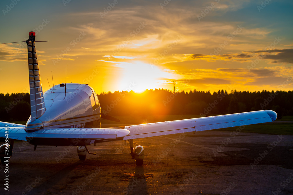 Rear view of a parked small plane on a sunset background. Silhouette of ...