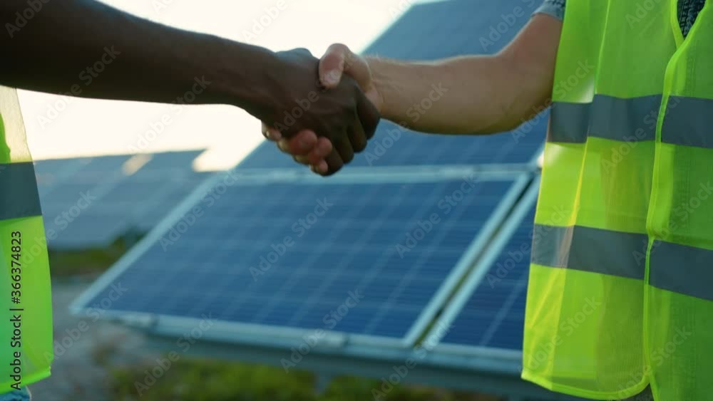 Close up two men shake hands at sunlight windmills installation ...