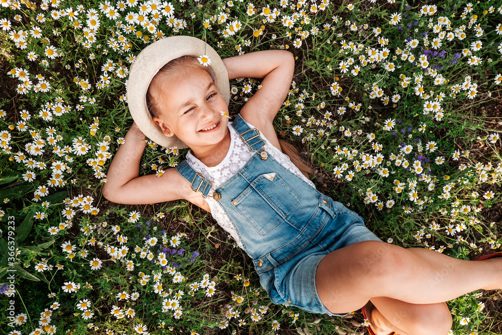 Pretty girl lying in daisy field and smiling to camera, unity with ...