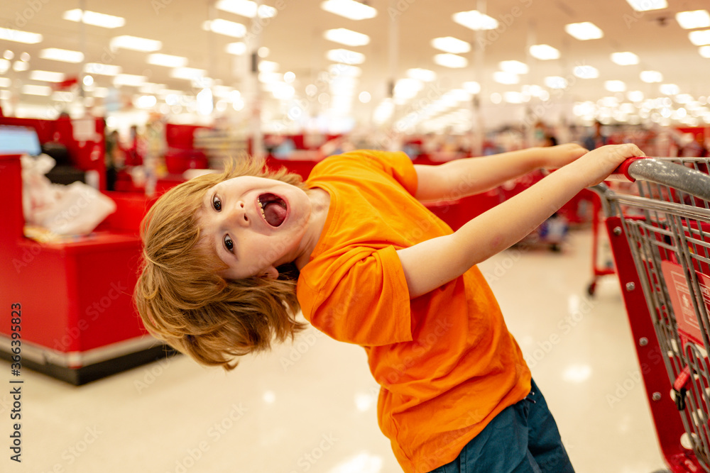 Funny customer boy child holdind trolley, shopping at supermarket ...
