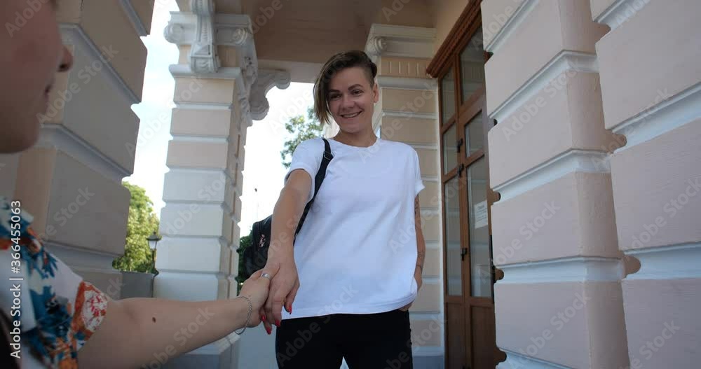 Female Same Sex Couple Meeting And Walking Downstairs Holding Hands