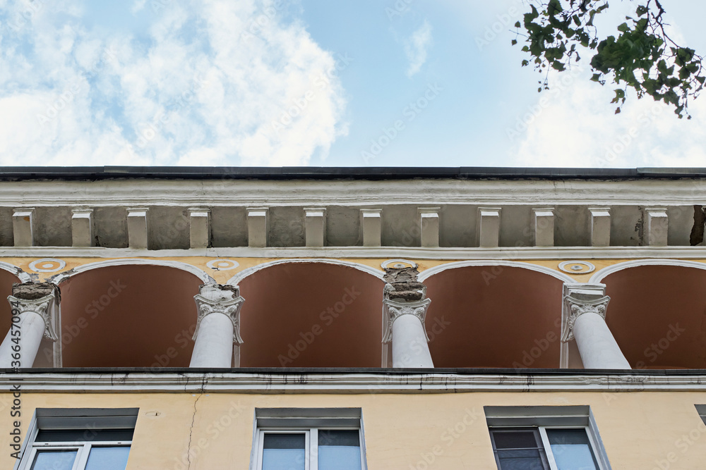 A multi-storey building with columns and carved balconies on a cloudy ...