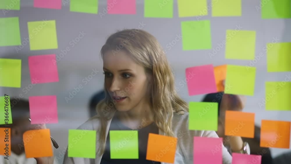 Young businesswoman office worker replacing sticky notes on planning ...
