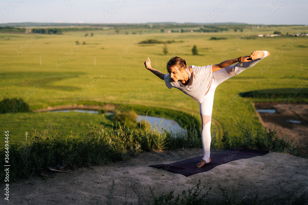 Sporty fit young woman practicing yoga on top of rock background of ...