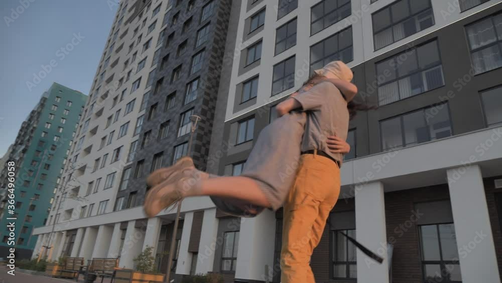 Shot from the lower angle, a young guy picks up a curly girl in his ...