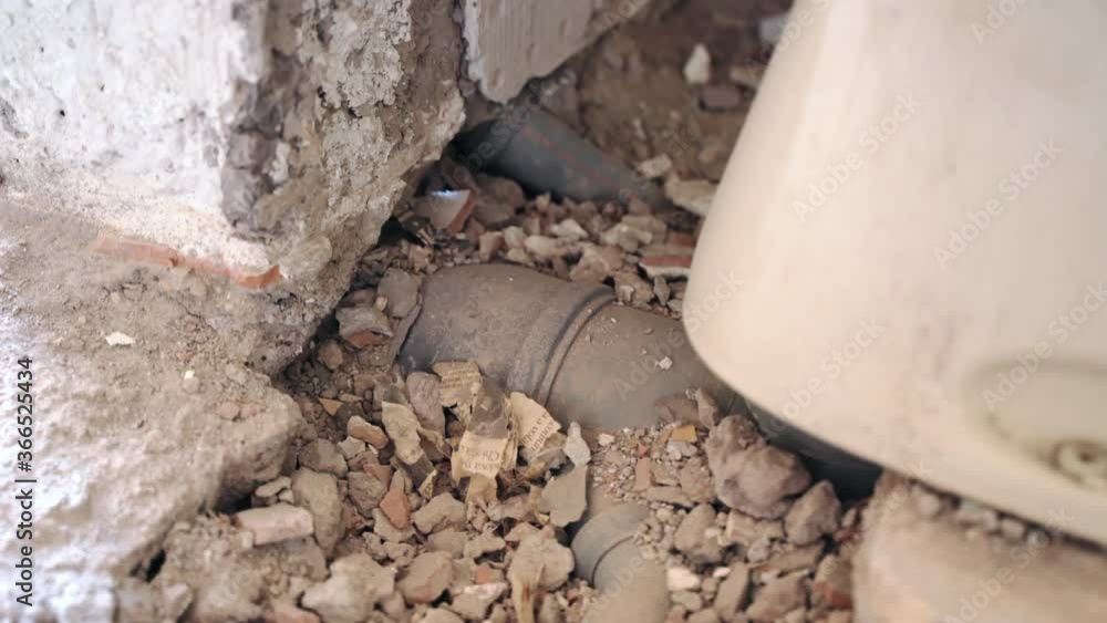 Close-up of hidden plastic sewerage pipe under the rusty toilet on ...