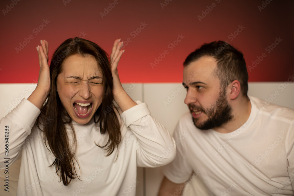 couple swearing in bed. Pretty brunette girl screaming covering ears ...