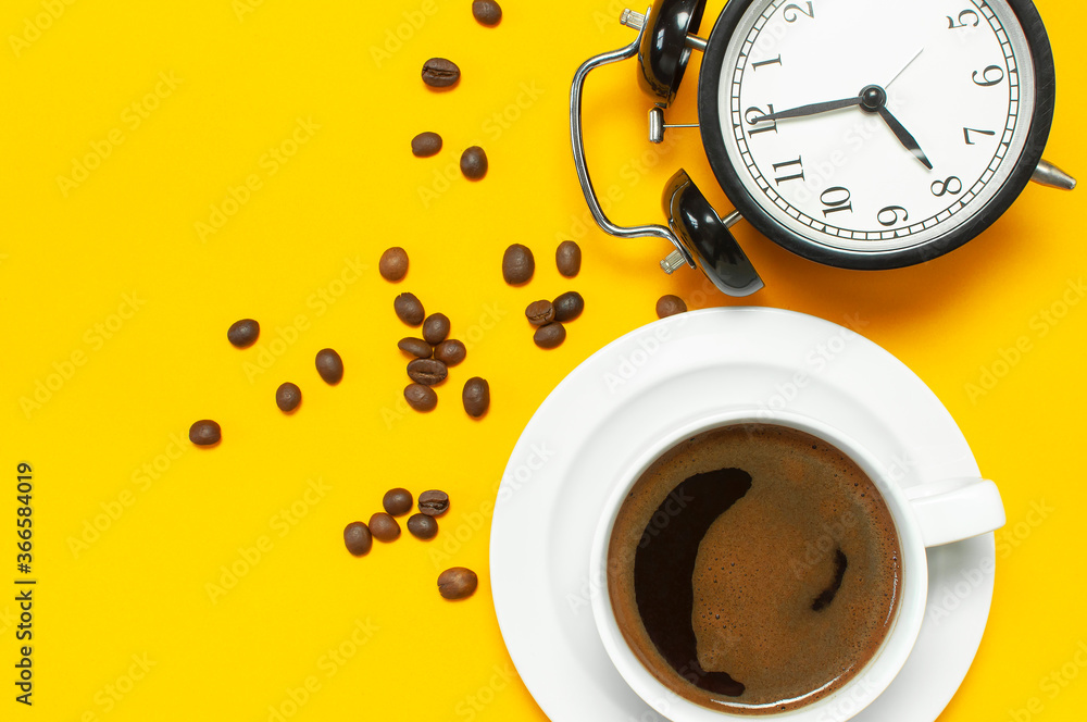 Cup of black coffee, coffee beans, black alarm clock on yellow ...