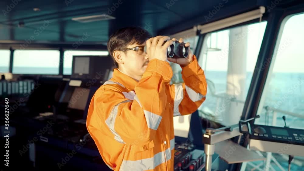 Filipino deck Officer on bridge of vessel or ship wearing coverall. He ...