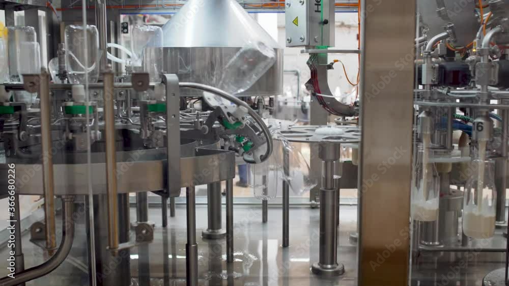Rotating transporter is pouring fresh milk into bottles. Automated ...
