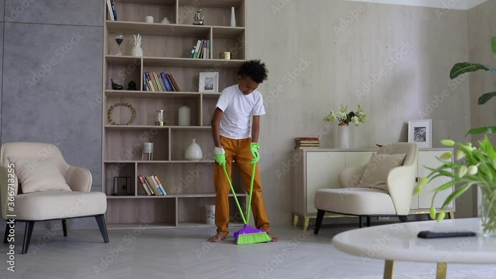 Front view of African American boy is cleaning his room during ...