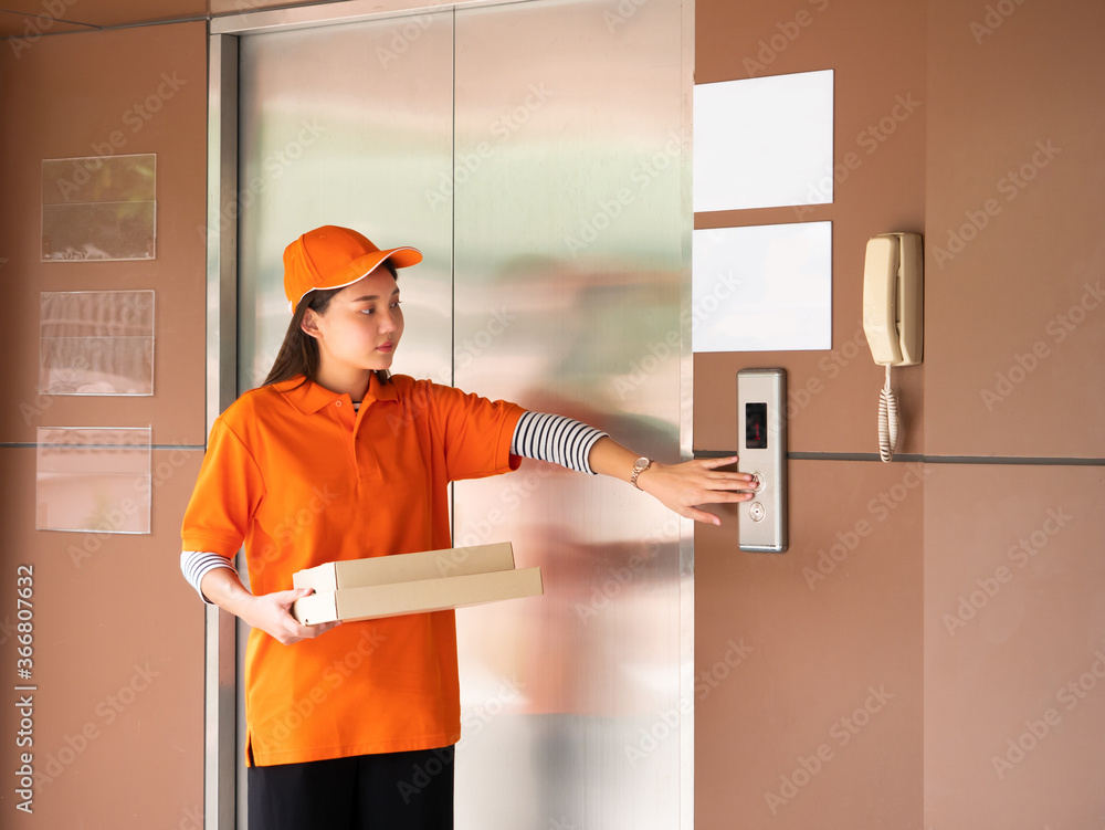 Asian young delivery girl push button lift or elevator switch at ...