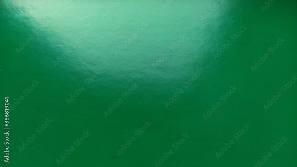 Green sheet of shiny colored paper. The reflective surface glares in ...