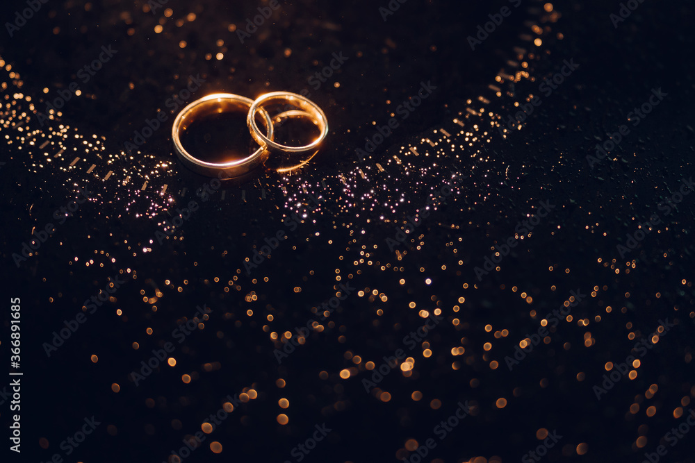gold wedding rings on black background with gold dust Stock Photo ...