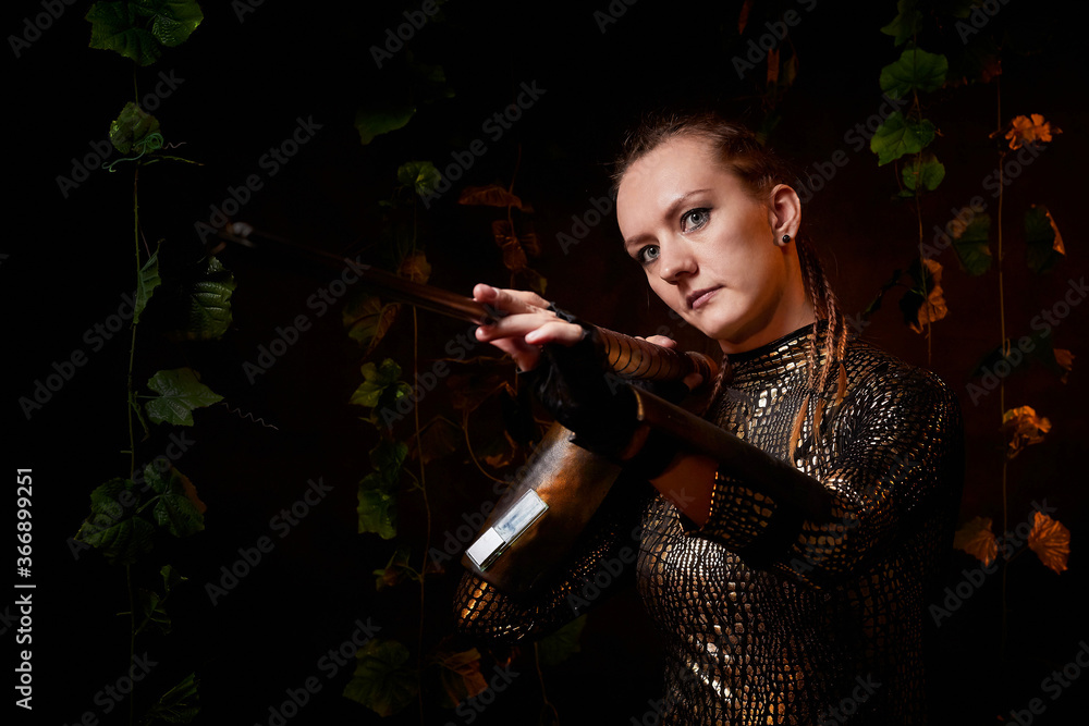 Valkyrie girl in shiny military armor and with a spear in a dark room ...