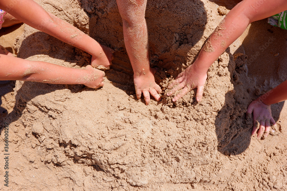 Children playing in the sand at the beach by digging a hole with their ...