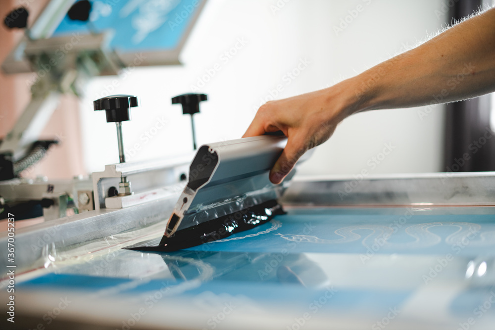 Cropped view of artisan holding squeegee with plastisol ink while ...