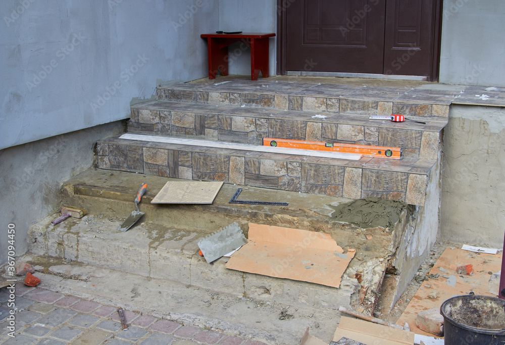 repair of concrete stairs,put on the stairs gray tiles, tools on the ...